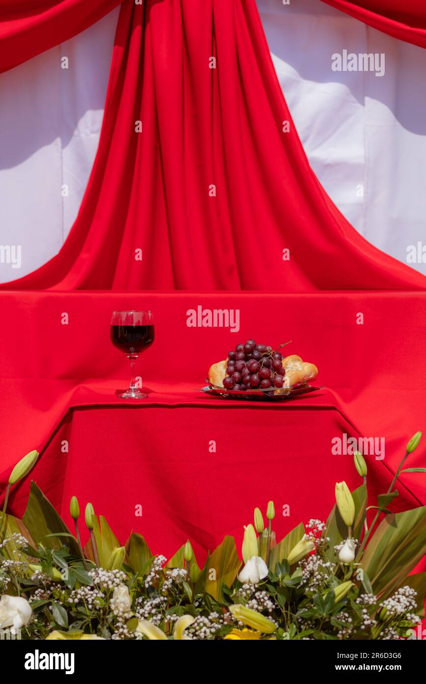 Wine glass, bread and grapes on red cloth in hard light. Symbolism of ...