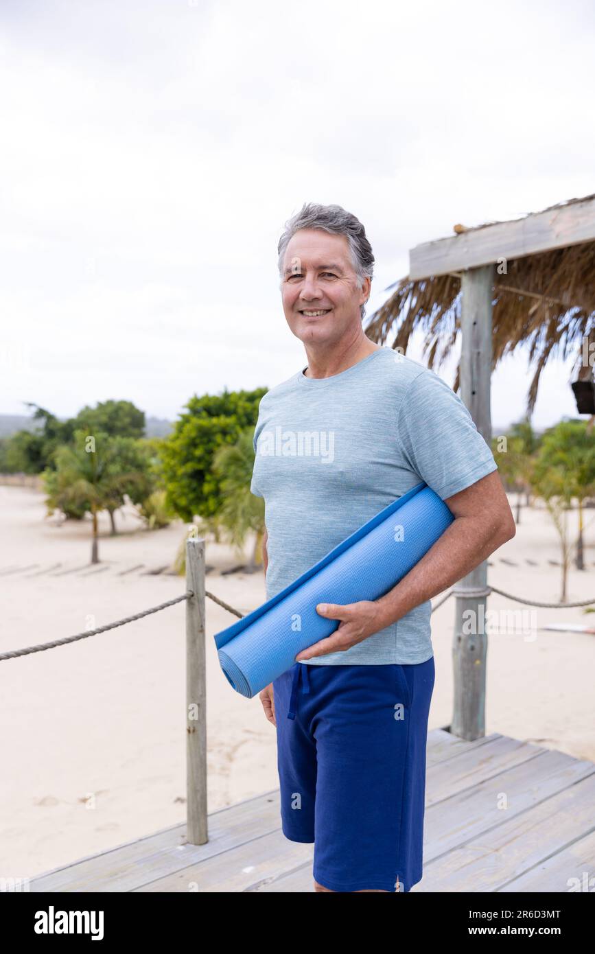 Portrait of smiling caucasian senior man with blue exercise mat ...