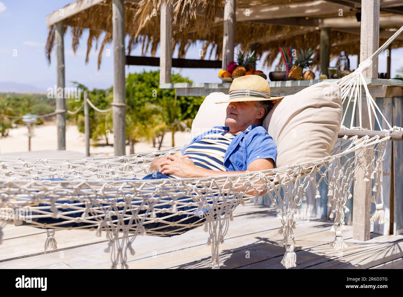 Caucasian senior man with hat on face sleeping on hammock at beach ...