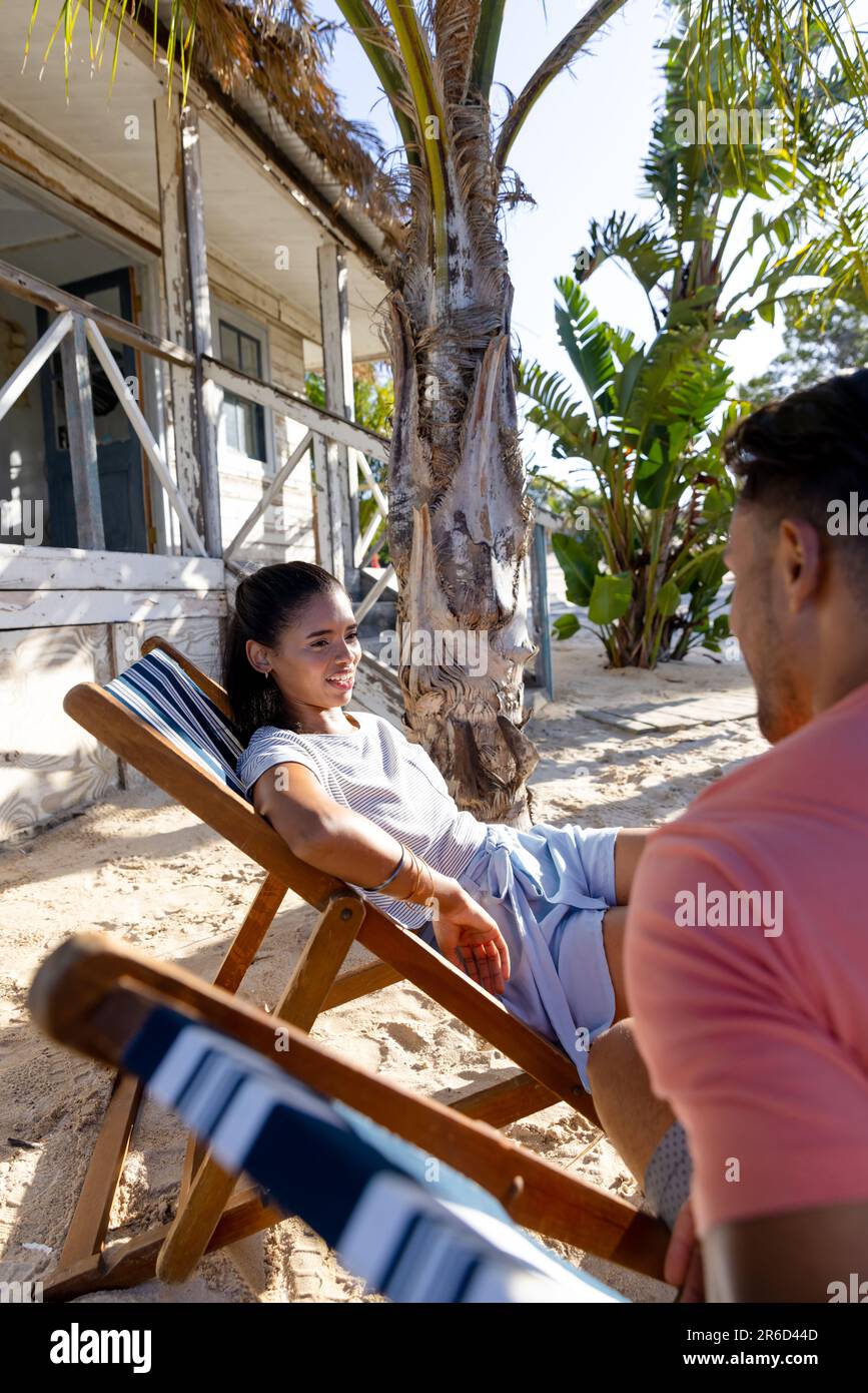 Caucasian young boyfriend and girlfriend talking while sitting on deck ...