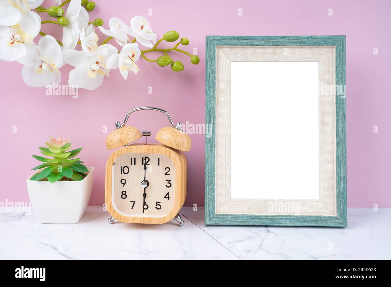 Blank picture frame and alarm clock on black floor with copy space and ...