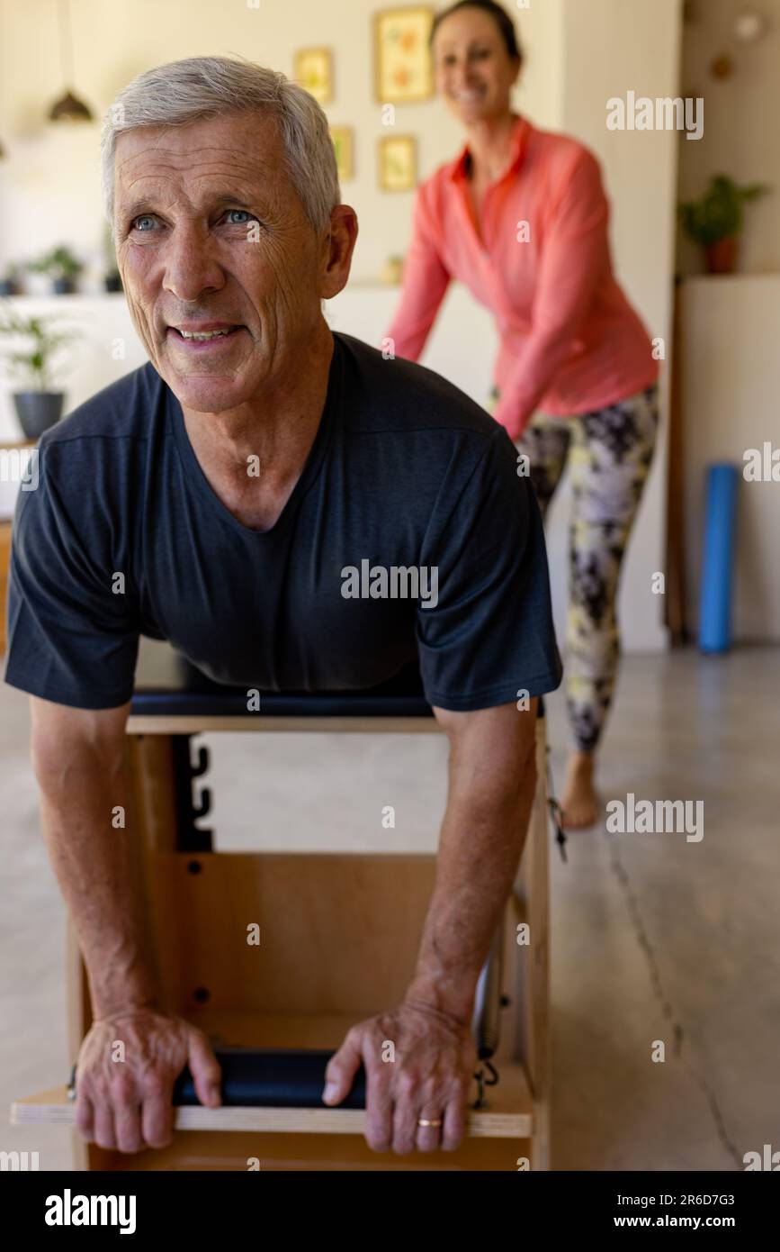 Focused caucasian senior man using exercise chair in pilates class with ...