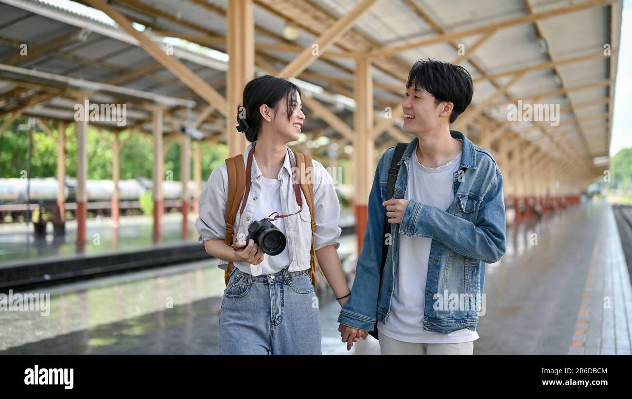 A lovely young Asian couple enjoys talking while walking along the ...