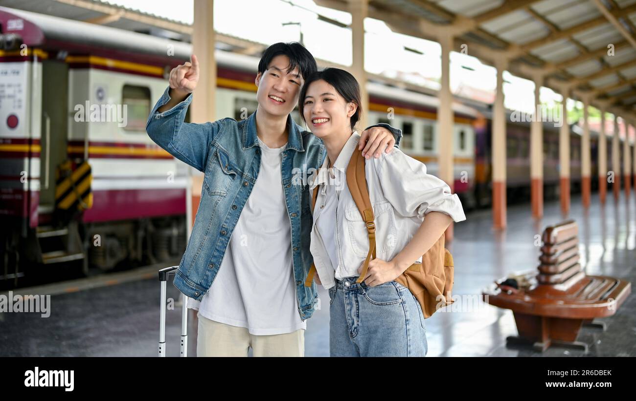 A happy and handsome young Asian man embraces his girlfriend while ...