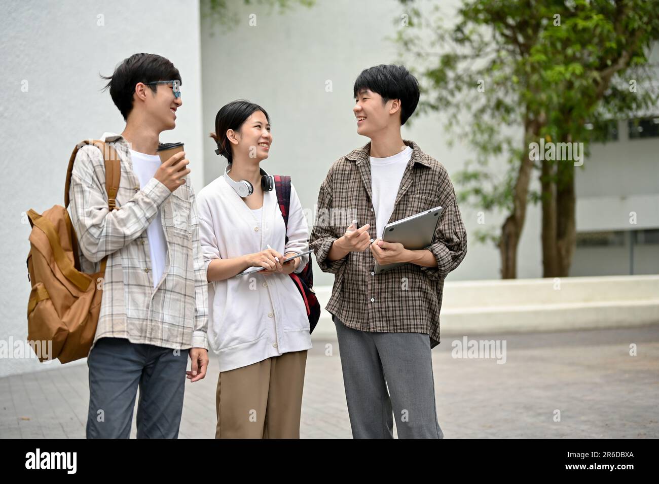 A group of cheerful young Asian college students enjoy talking and sharing their ideas while ...
