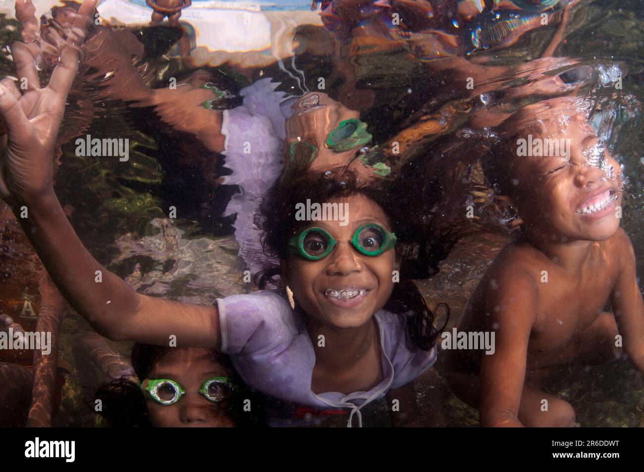 Kids with goggles underwater and making hand signals, Pier, Reta Island ...