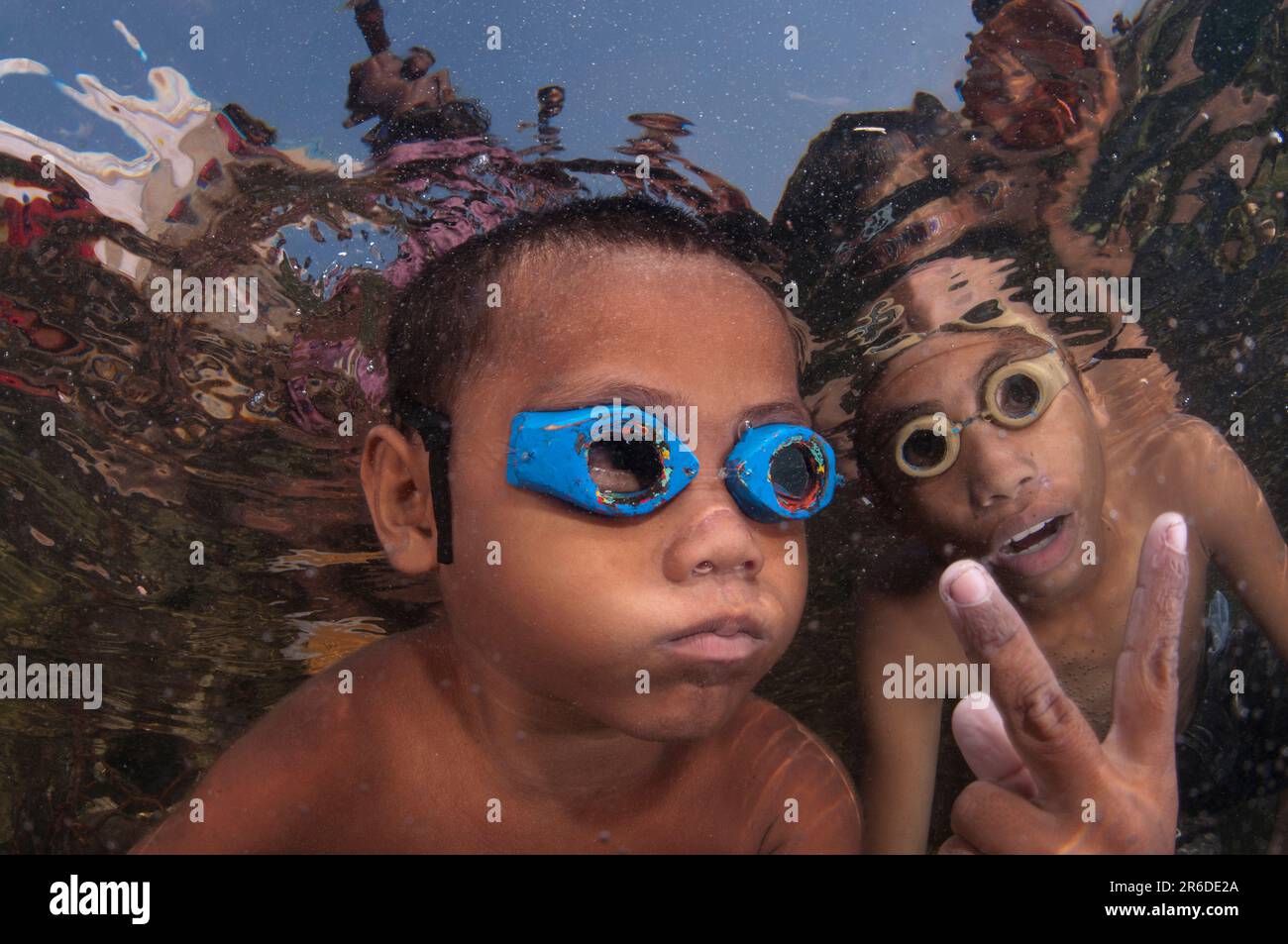Boys with goggles underwater making hand signals with people on pier ...