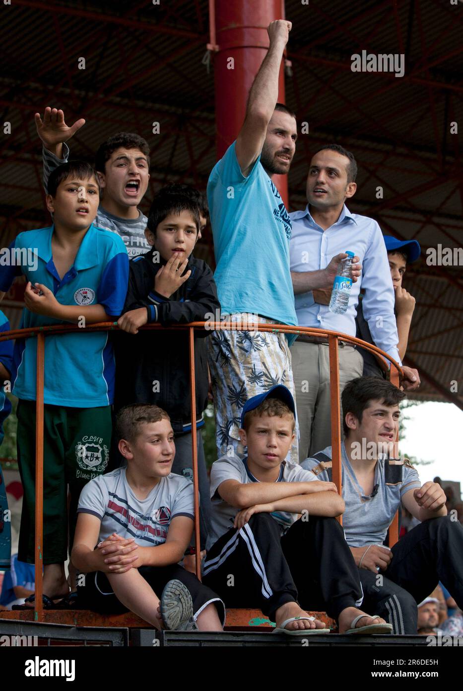 A group of Turkish men and boys watch competition from a grandstand at ...