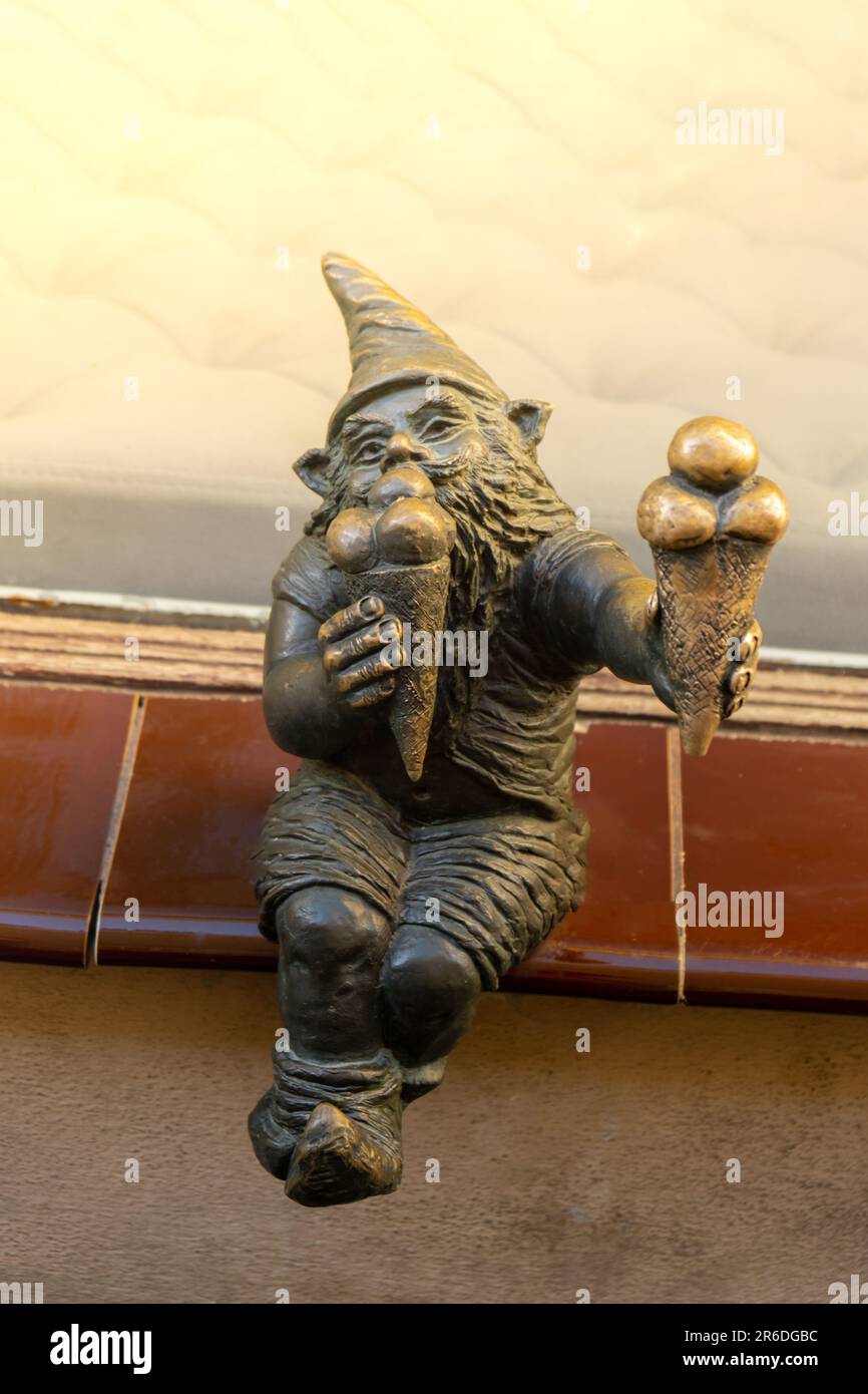 Dwarf eats ice cream on the windowsill of an old confectionery. Small ...