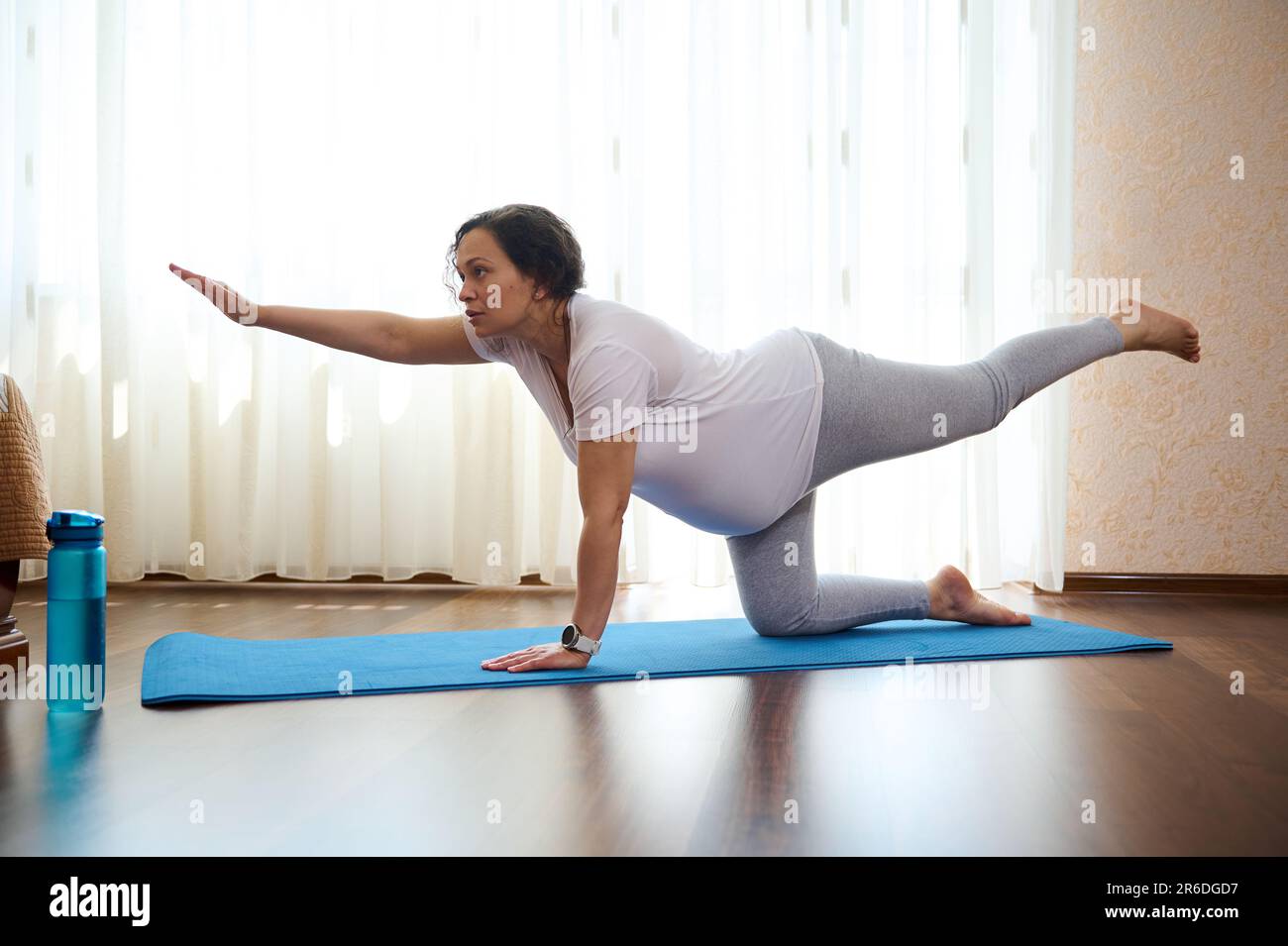 Pregnant woman doing sunbird, bird-dog pose indoors. Prenatal ...