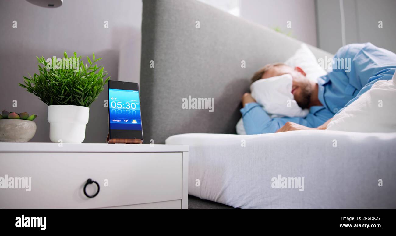 Man Waking Up With Alarm On Mobile Phone At Home Stock Photo - Alamy