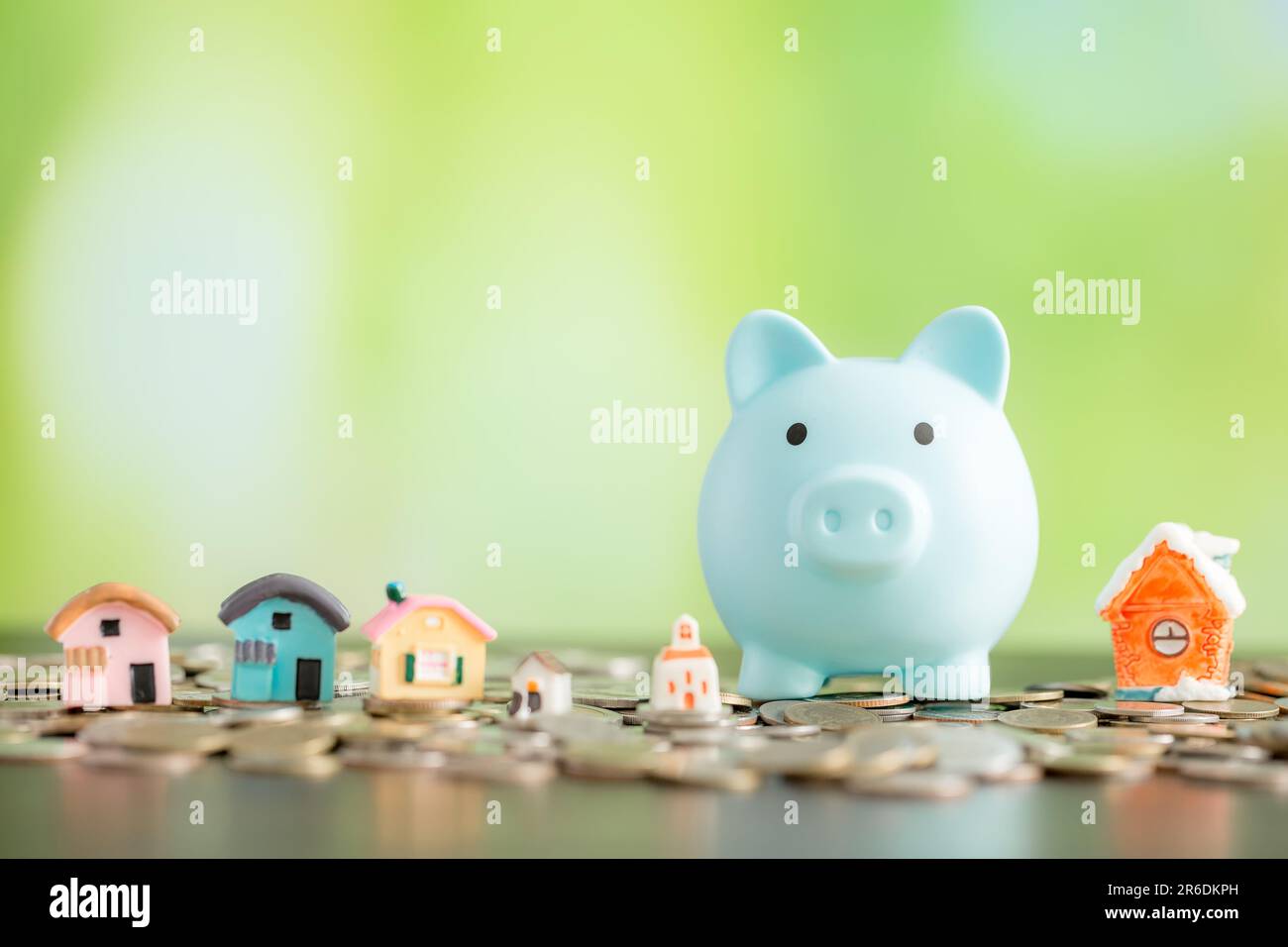 Mini house with piggy bank and coins money on natural green background ...