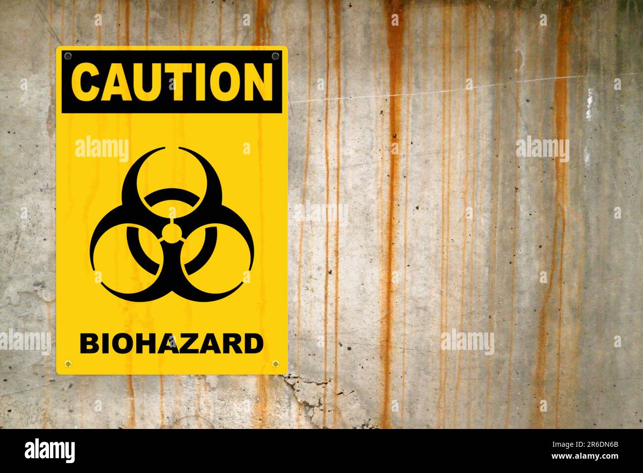 Yellow warning sign screwed to a concrete wall to warn about a threat ...