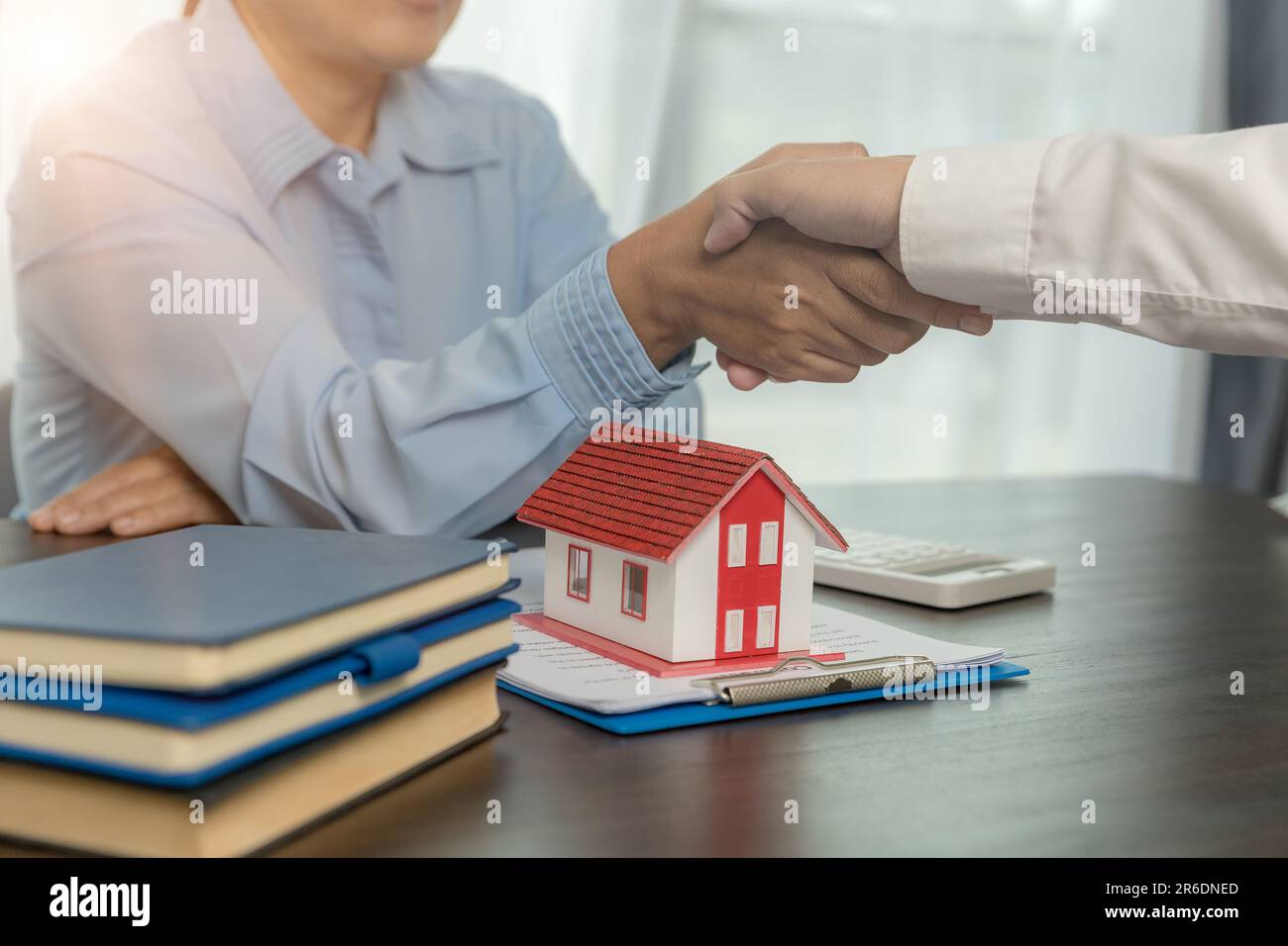 Estate agent shaking hands with client after contract signature and ...