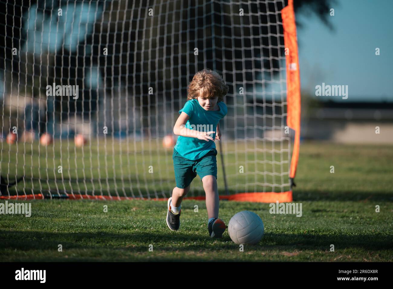 Boy child kicking football on the sports field during soccer match. Boy ...