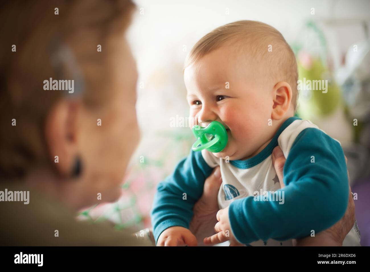 A grandmother holds her smiling grandson baby in her arms. Satisfied ...