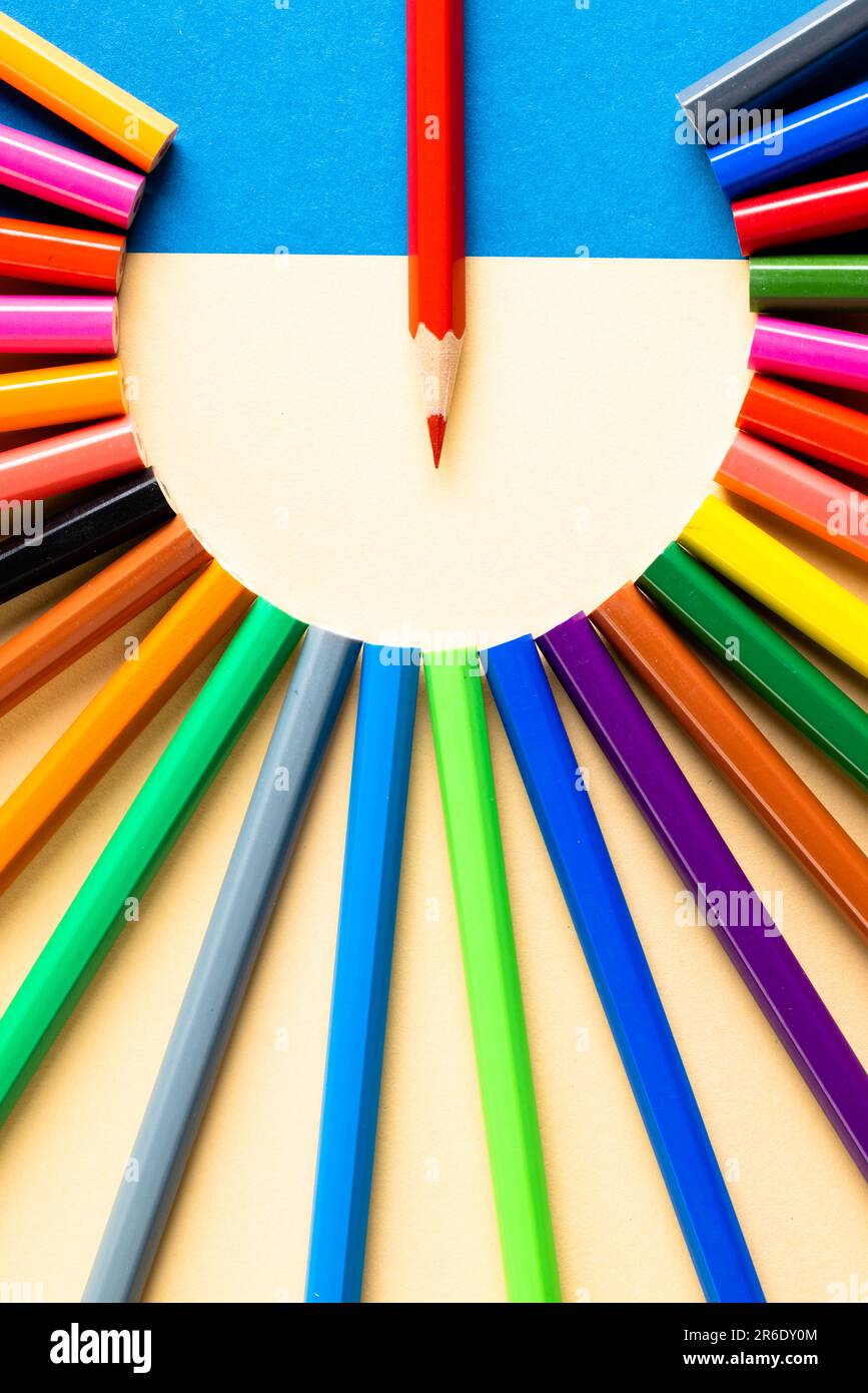 Close up of multi coloured pencils in circle and copy space on blue and ...