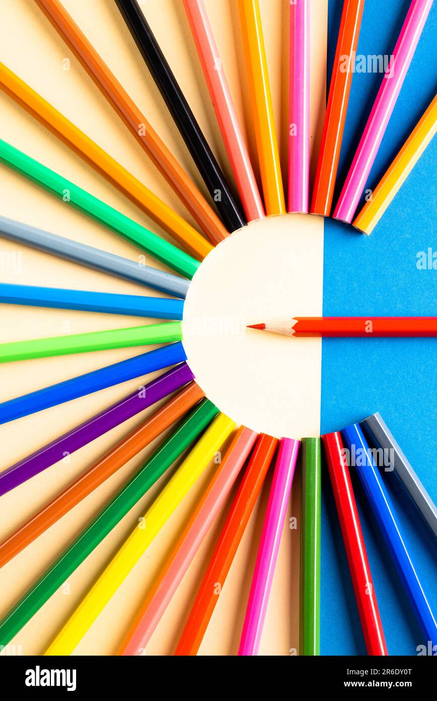 Close up of multi coloured pencils in circle and copy space on blue and ...