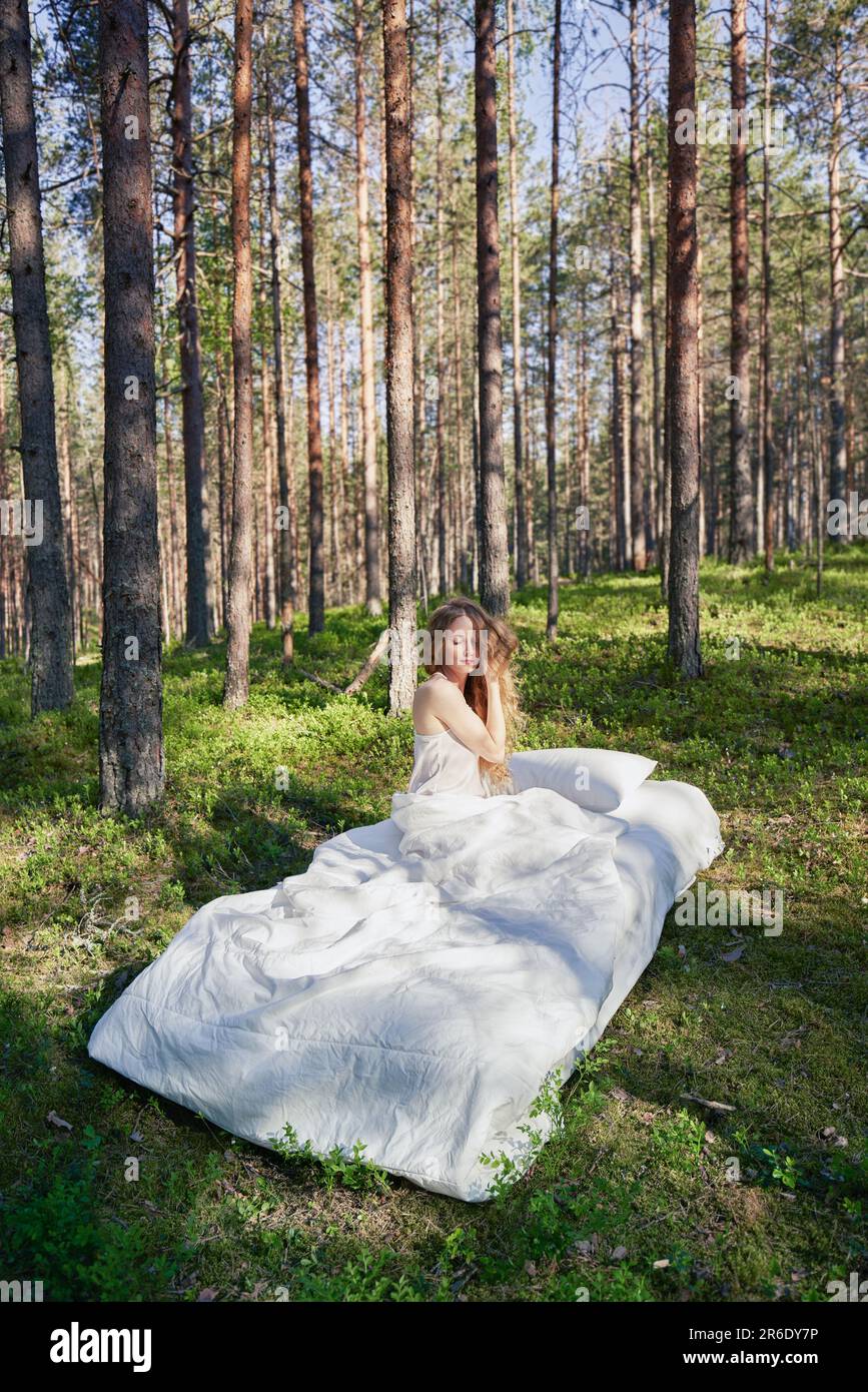 Woman sleeps on a mattress in the summer forest. The girl is resting in ...