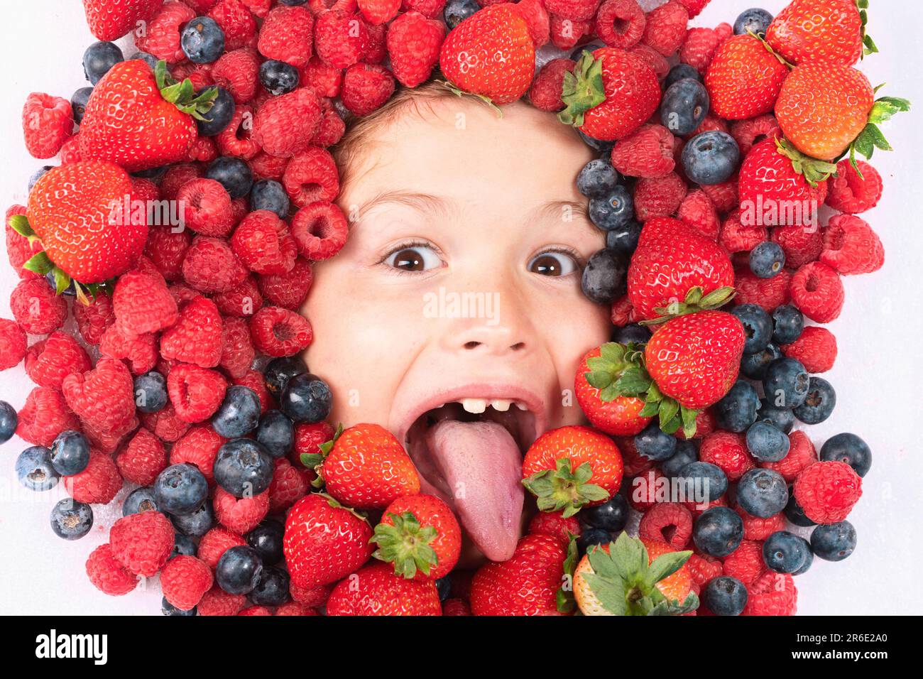 Summer fruits. Berries with kids face close-up. Top view of child face ...