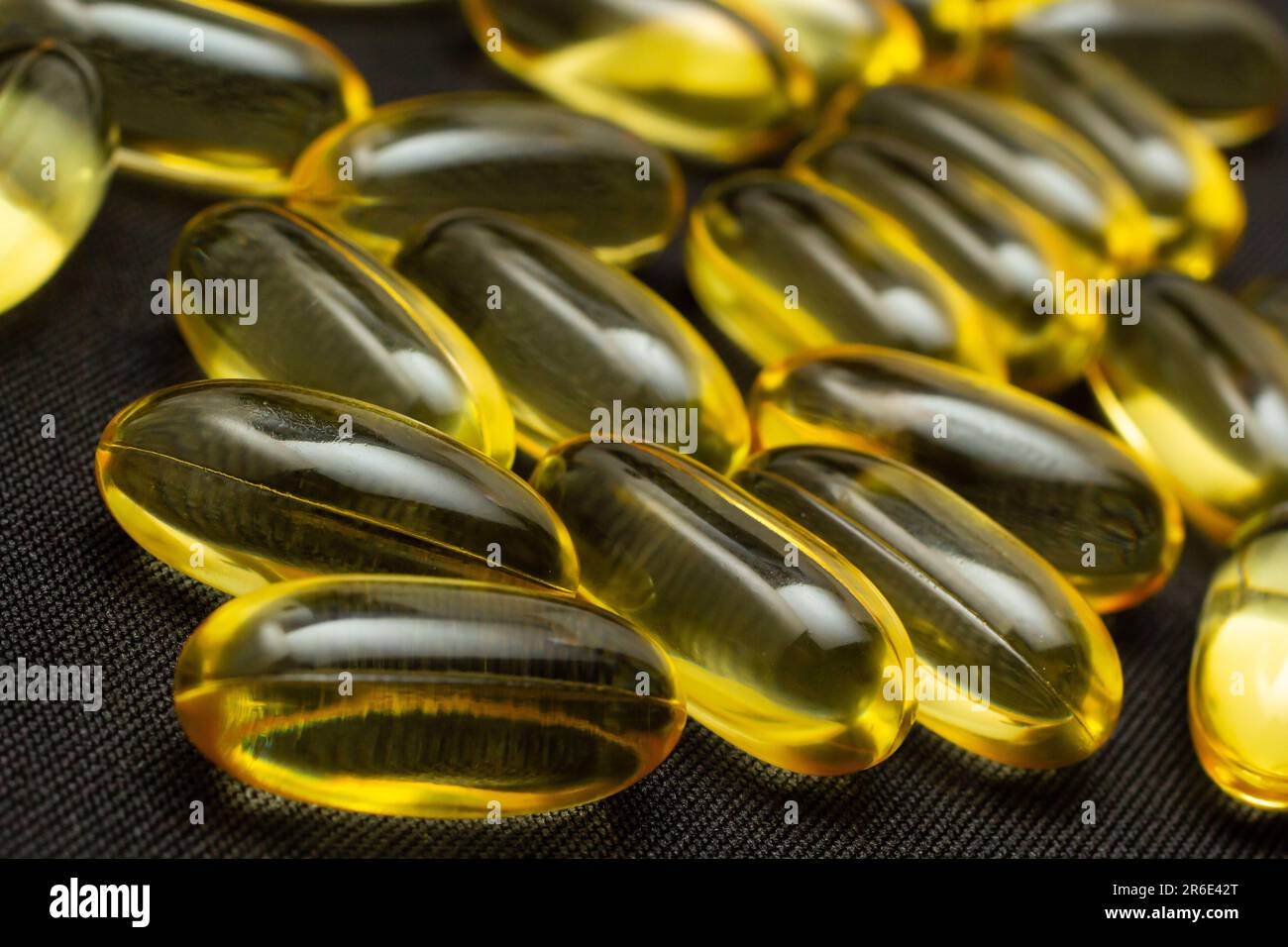 Macro Close up of Omega 3 gel capsule on a reflective black background ...