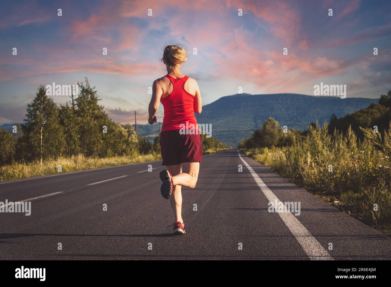 Fitness blonde woman running on the asphalt road at the mountains Stock ...
