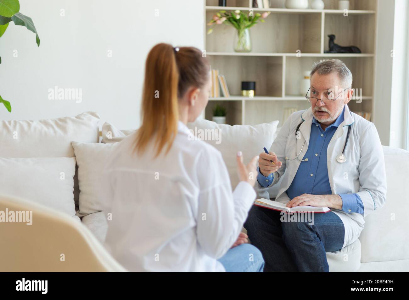 Senior man doctor examining yound woman in doctor office or at home ...