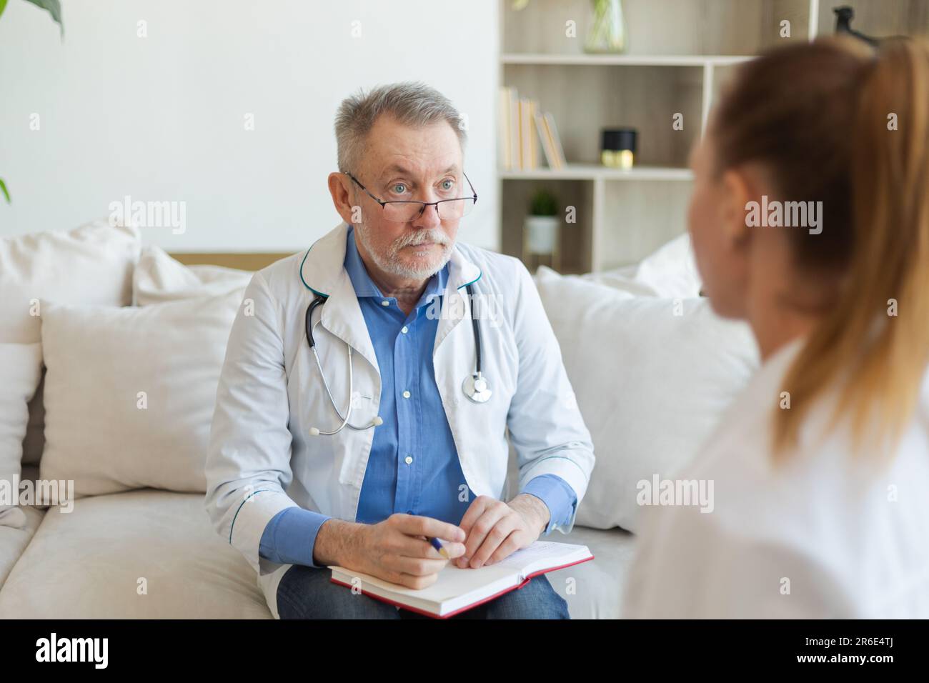 Senior man doctor examining yound woman in doctor office or at home ...