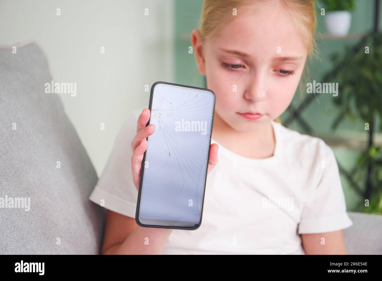 A sad girl is sitting with a broken mobile phone. The main focus is on ...