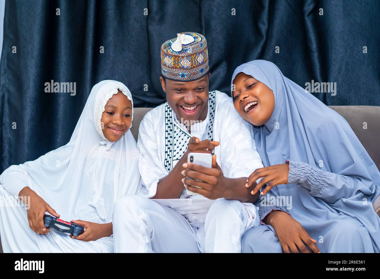 Excited beautiful family seated together making use of a mobile phone ...