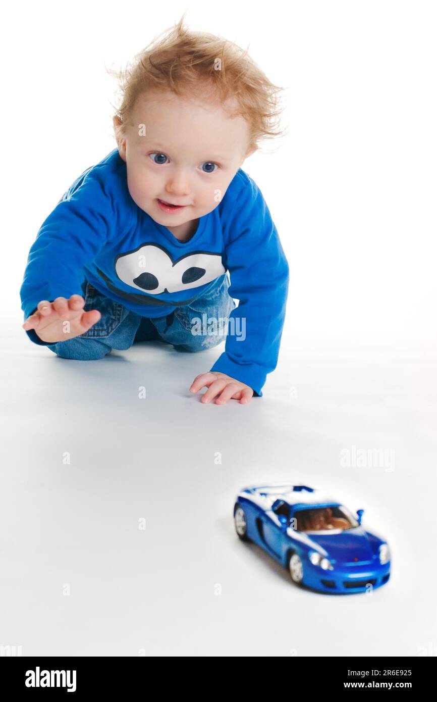 Baby plays with blue car toy on white background Stock Photo - Alamy