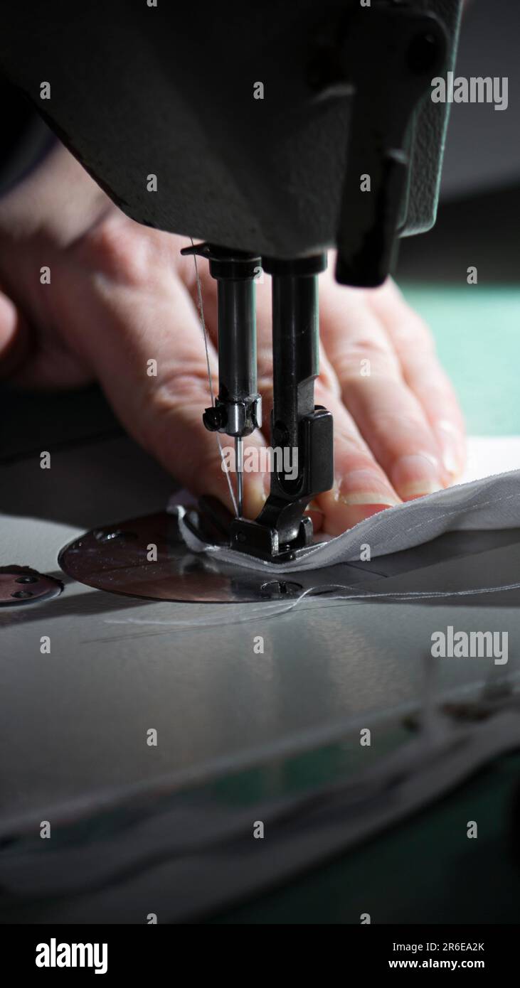 A closeup of a woman using a sewing machine to sew fabric together ...