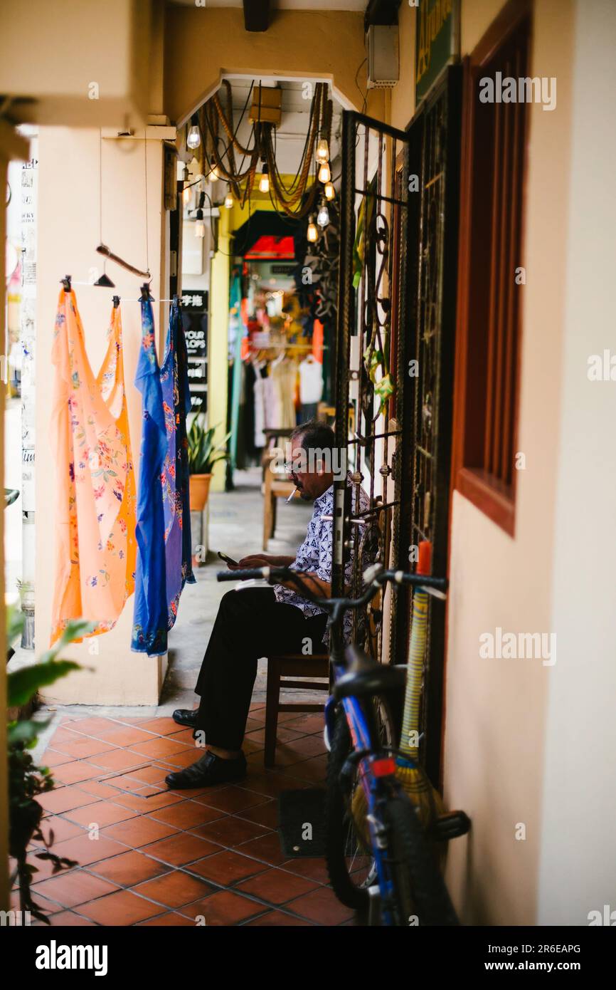 Man sits outside clothing store in colorful shopping district Stock ...