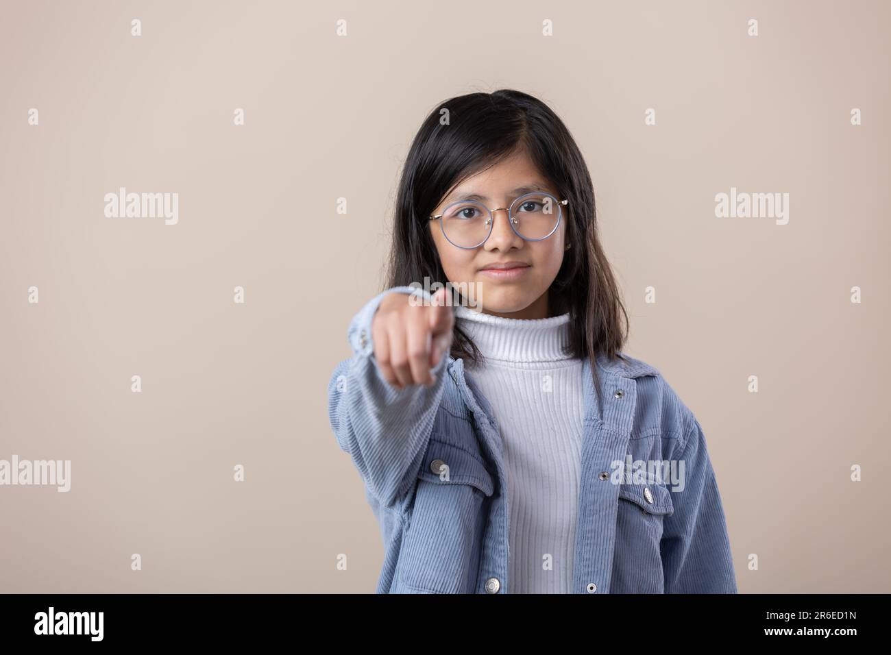 A young woman with glasses on looks at the camera with a puzzled ...