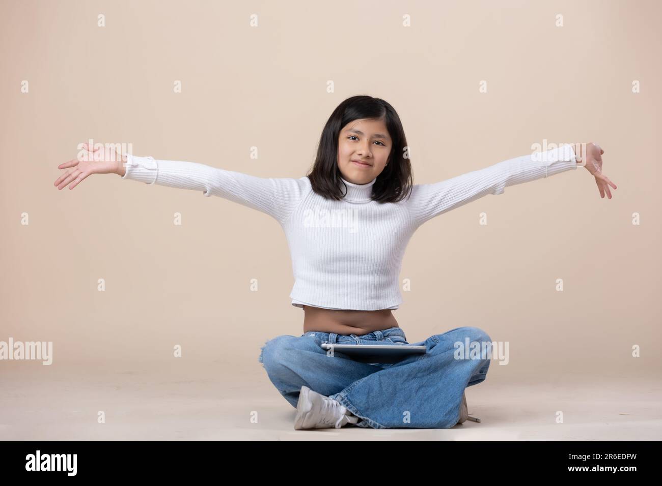 A young woman in a white shirt is seated on a white mat in an outdoor ...