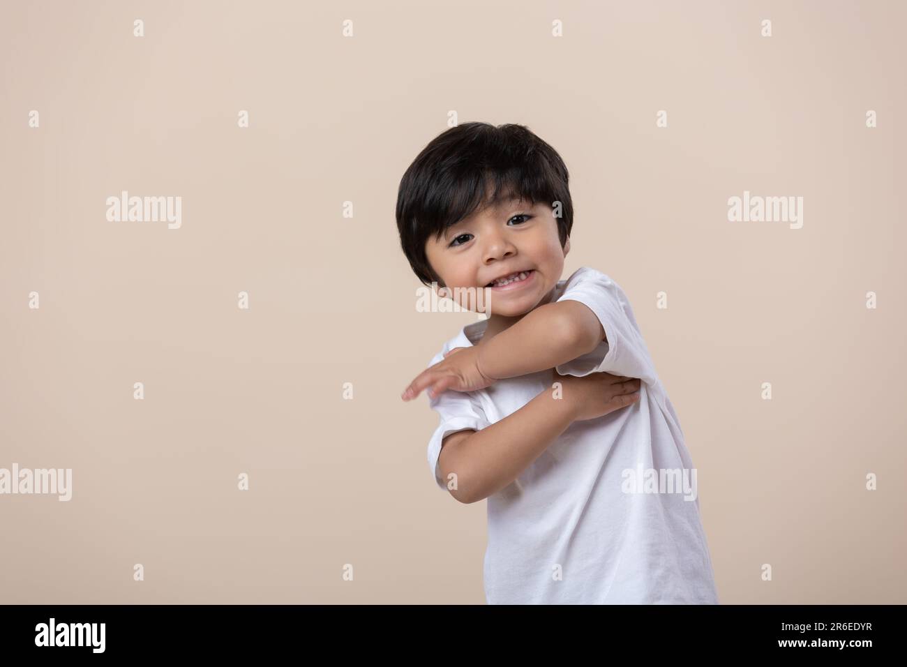 A young Caucasian boy wearing a white shirt stands in a vibrant outdoor ...