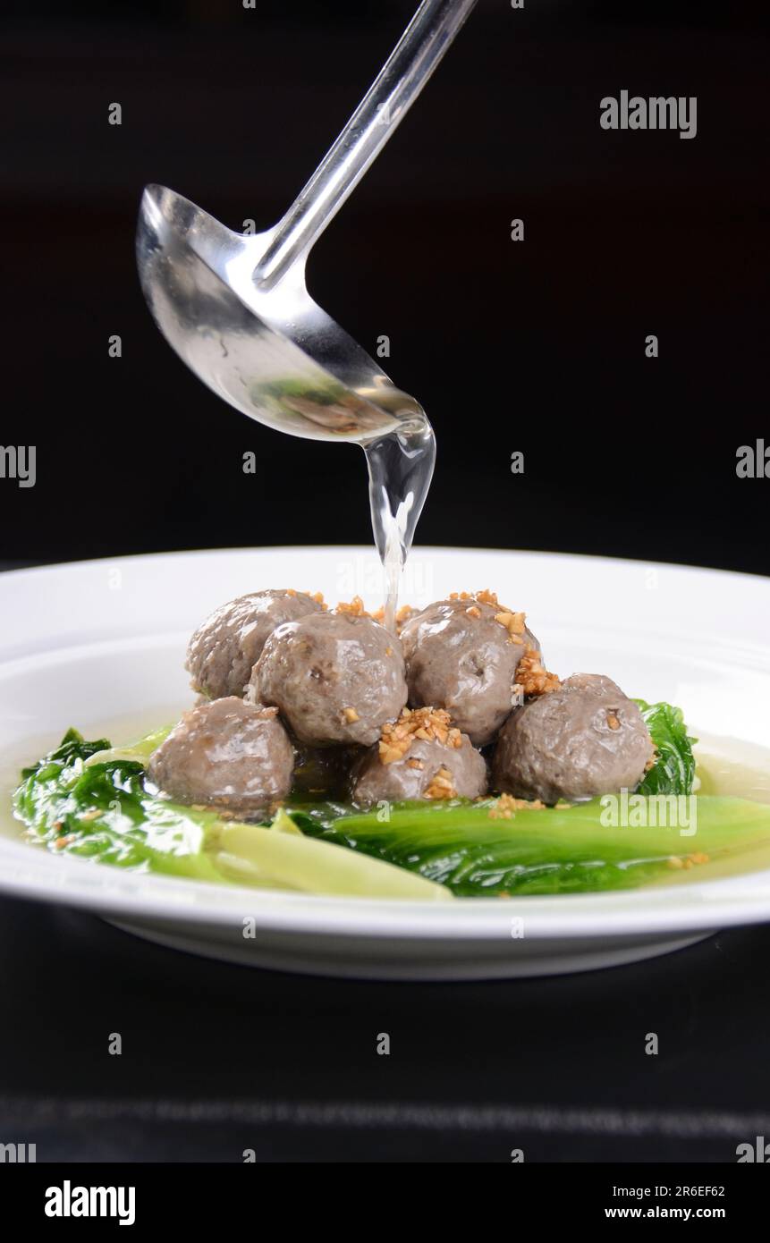 A water pouring over a delicious Chinese meal of meatballs with fresh ...