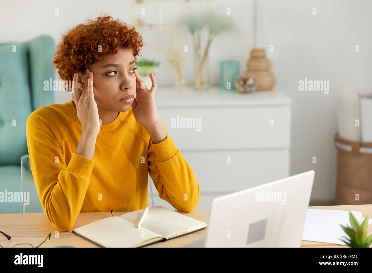 African woman touching temples experiencing stress. Girl at home office ...