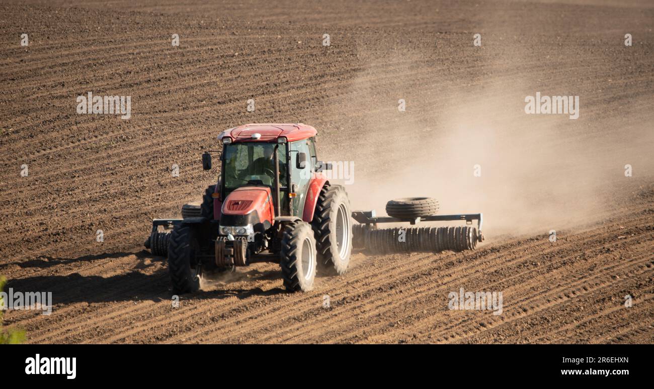 modern tractor equipped with a cultivator plows a field in preparation ...
