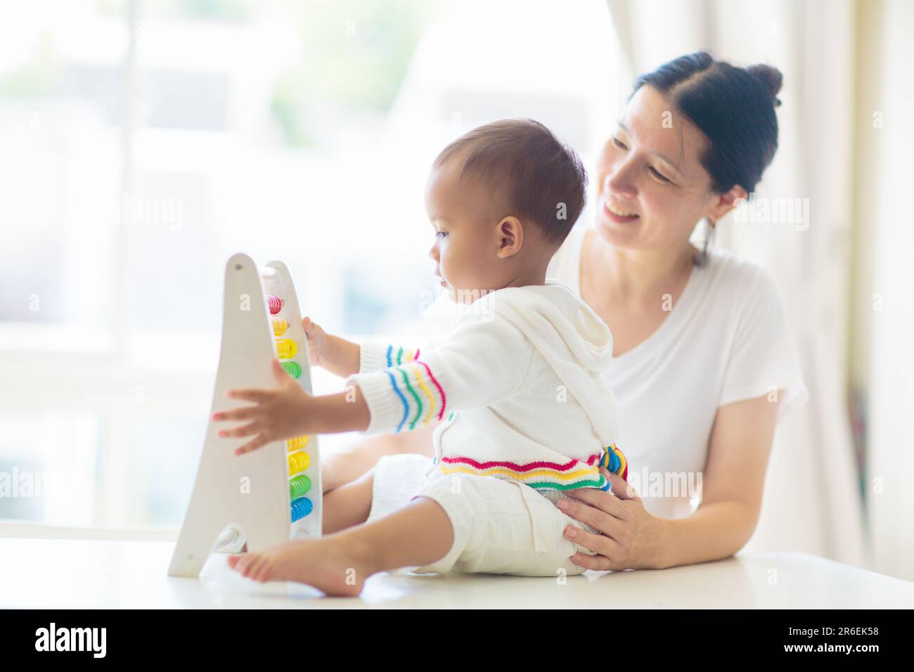 Baby boy and mother playing with wooden abacus. Kids learn to count ...
