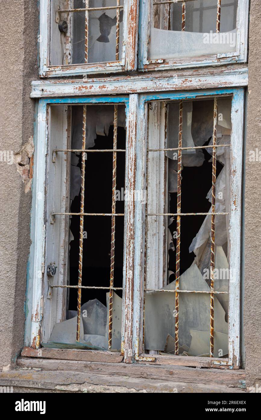 Old window with worn wooden shutters and broken glass on exterior wall ...