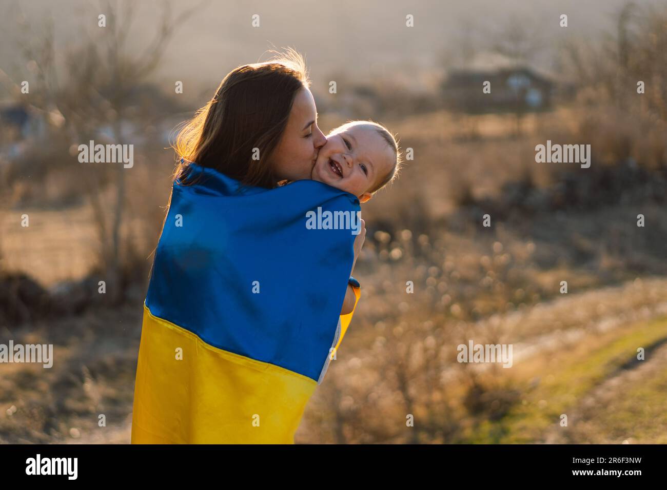 Woman hugs her little son wrapped in yellow and blue flag of Ukraine in ...