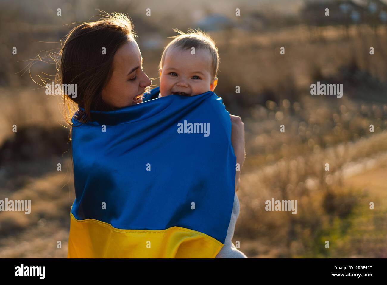 Woman hugs her little son wrapped in yellow and blue flag of Ukraine in ...