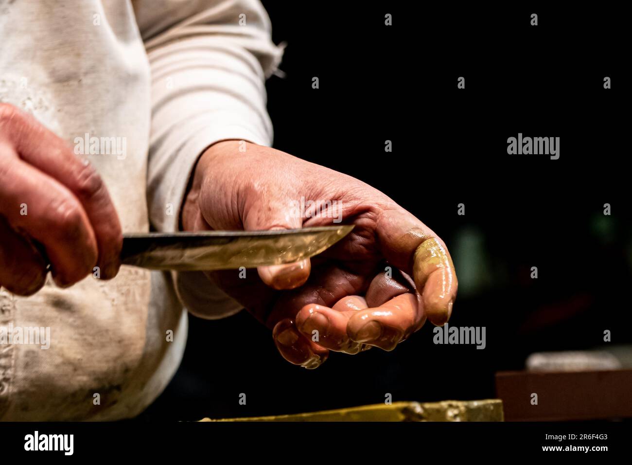 A swordsmith carefully cleaning a vintage, rusty knife, holding it ...