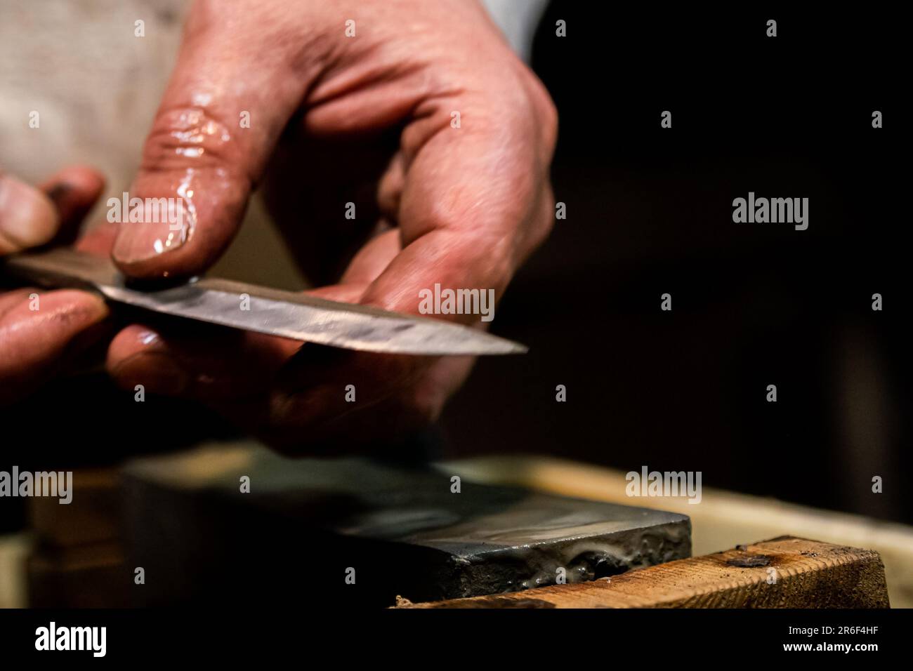 Two hands grasping a vintage knife with a sharp blade in a wooden ...