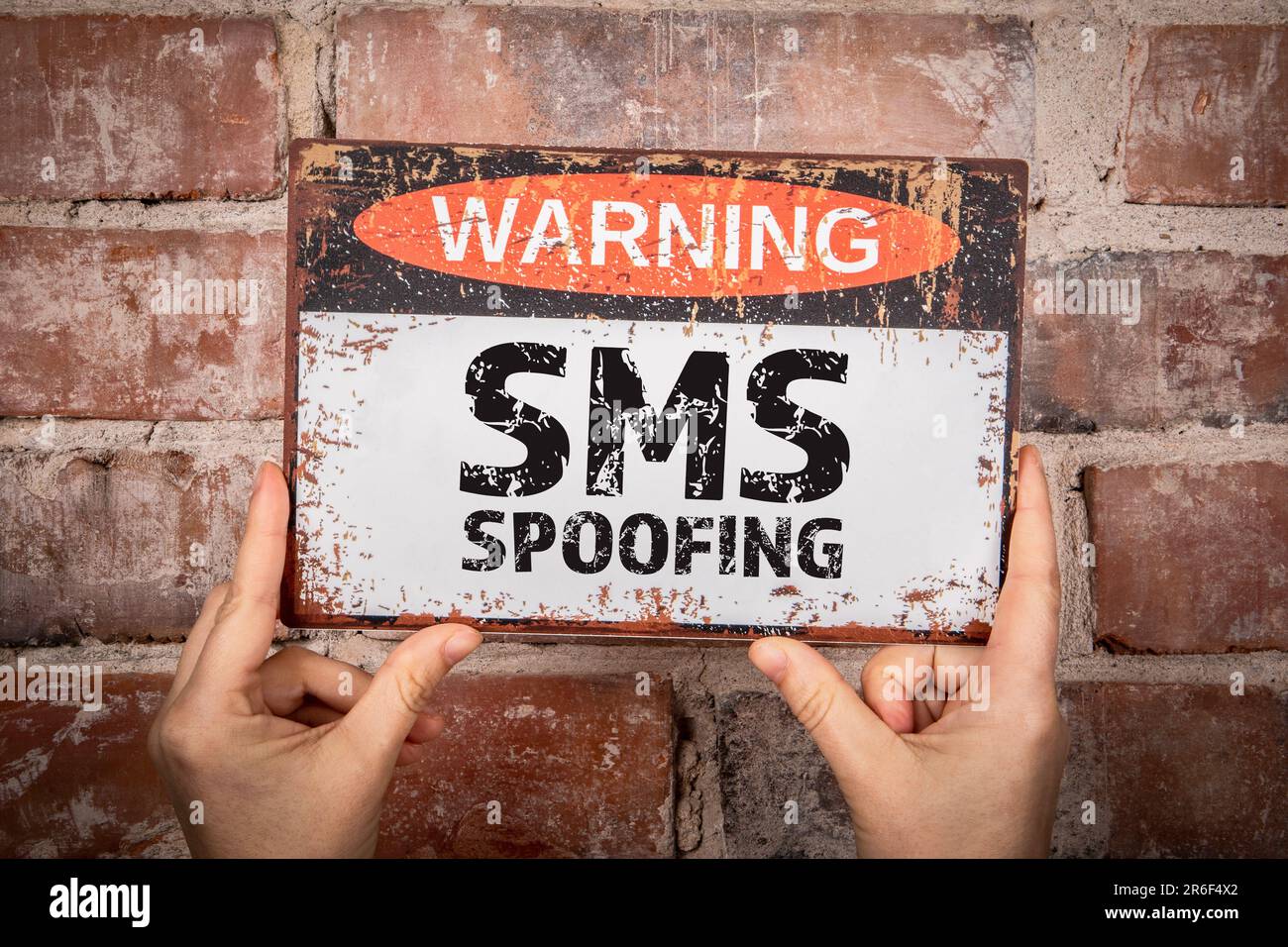 SMS SPOOFING. A woman is holding a warning sign with text. Red brick ...