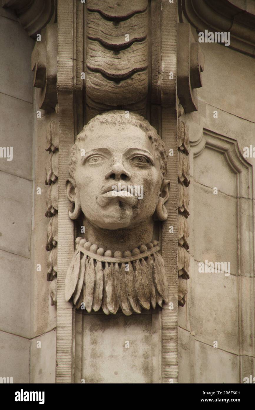 An aged carved head is prominently displayed on the face of a building ...