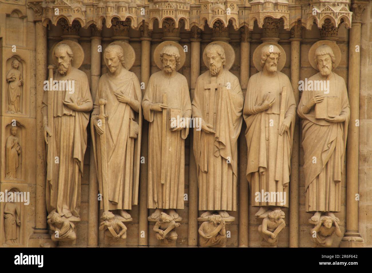 Four bronze statues of human figures standing in a row in front of a ...