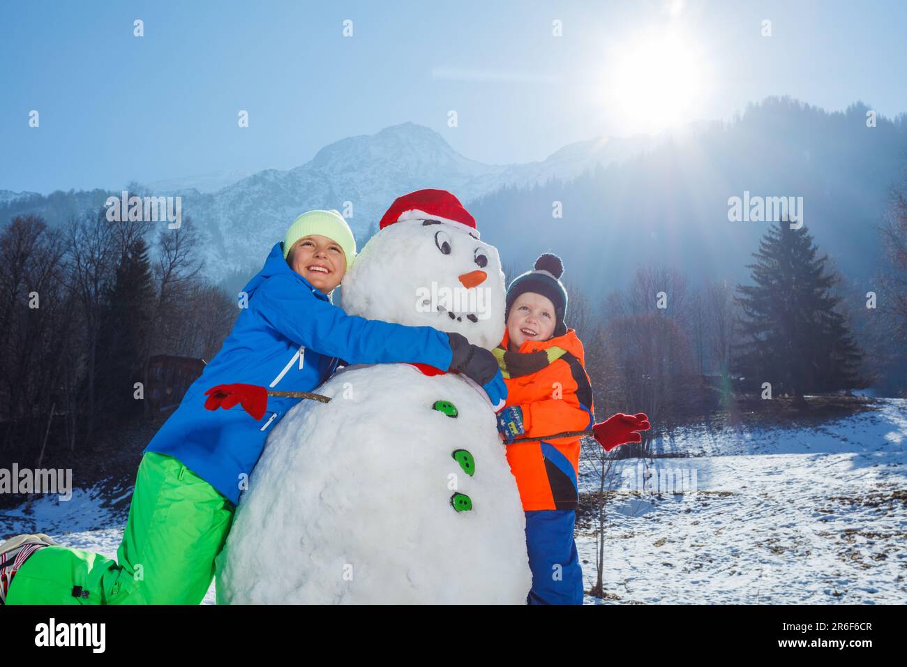 Two happy kids boys brothers play with funny snowman Stock Photo - Alamy