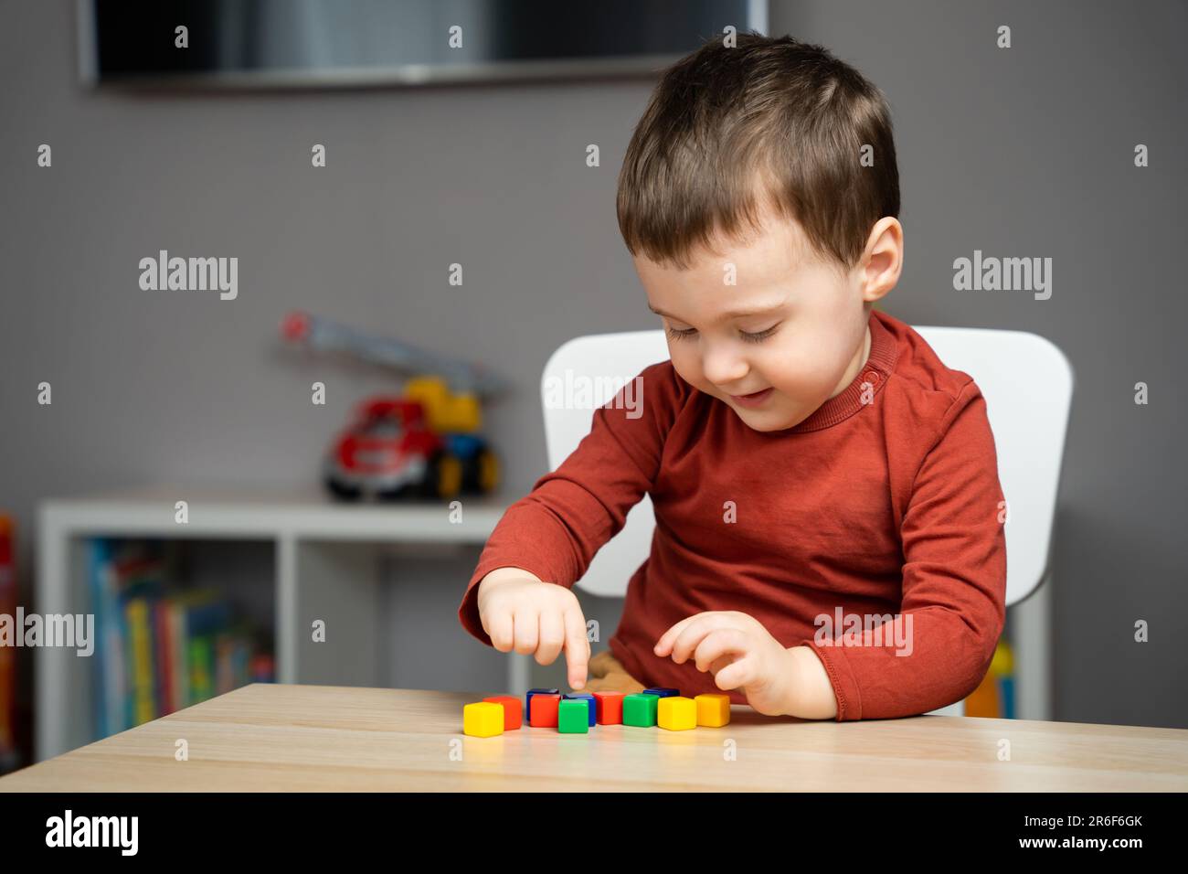 A happy cute little toddler boy of two years old sits at a children's ...